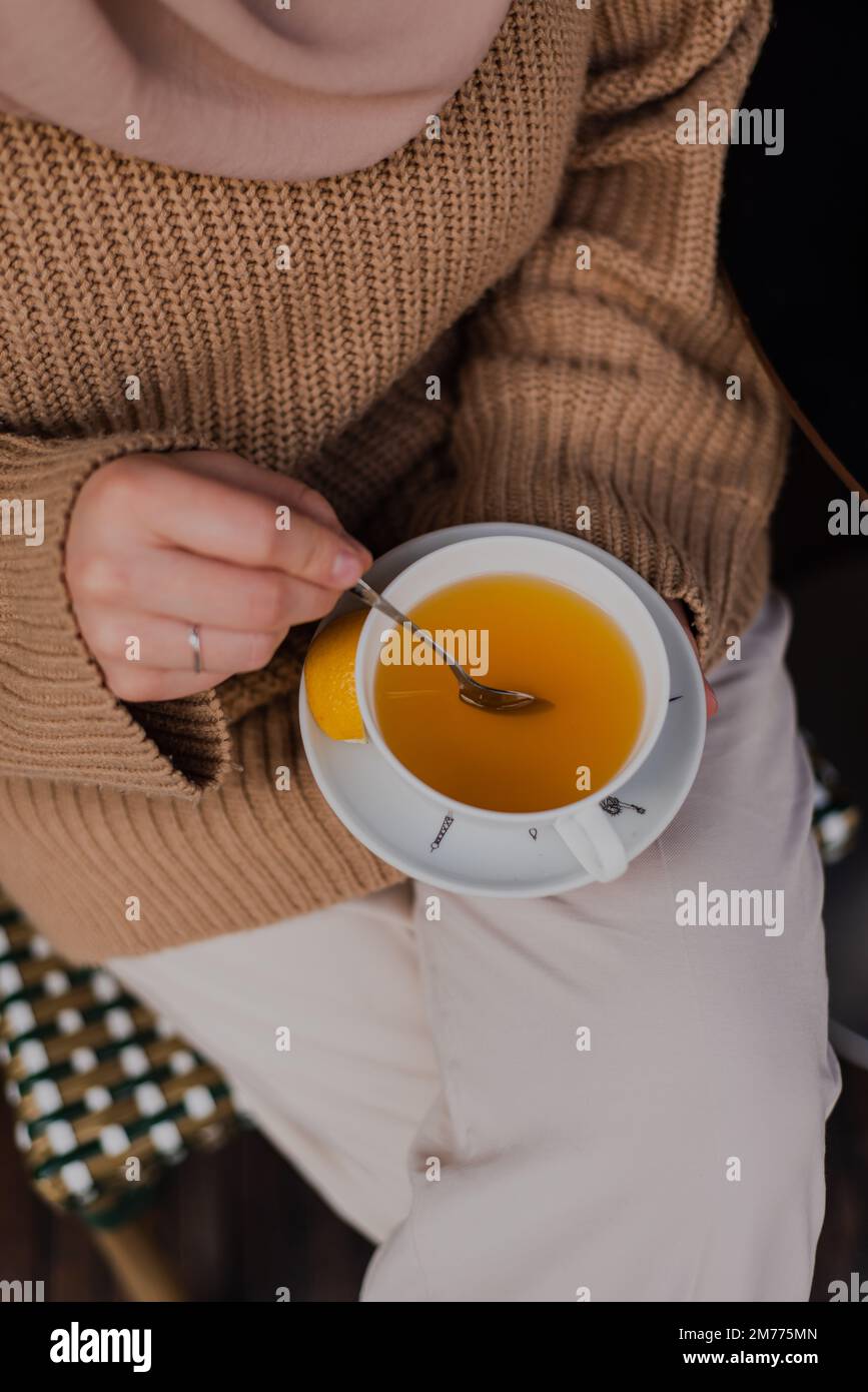 A vertical shot of a female hand stirring her tea sitting in a cafe ...
