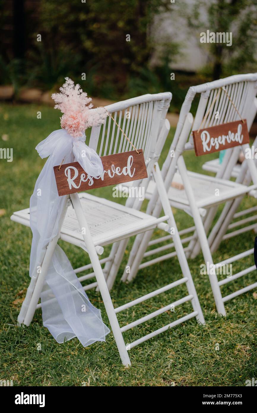A vertical shot of decorative reserved chairs at an outdoor wedding ...