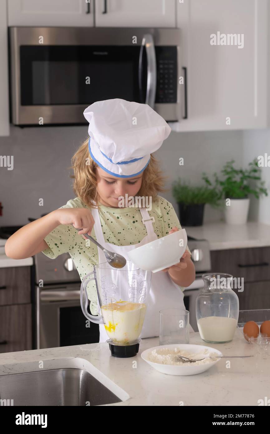 Funny child stand at kitchen table have fun baking, doing bakery ...