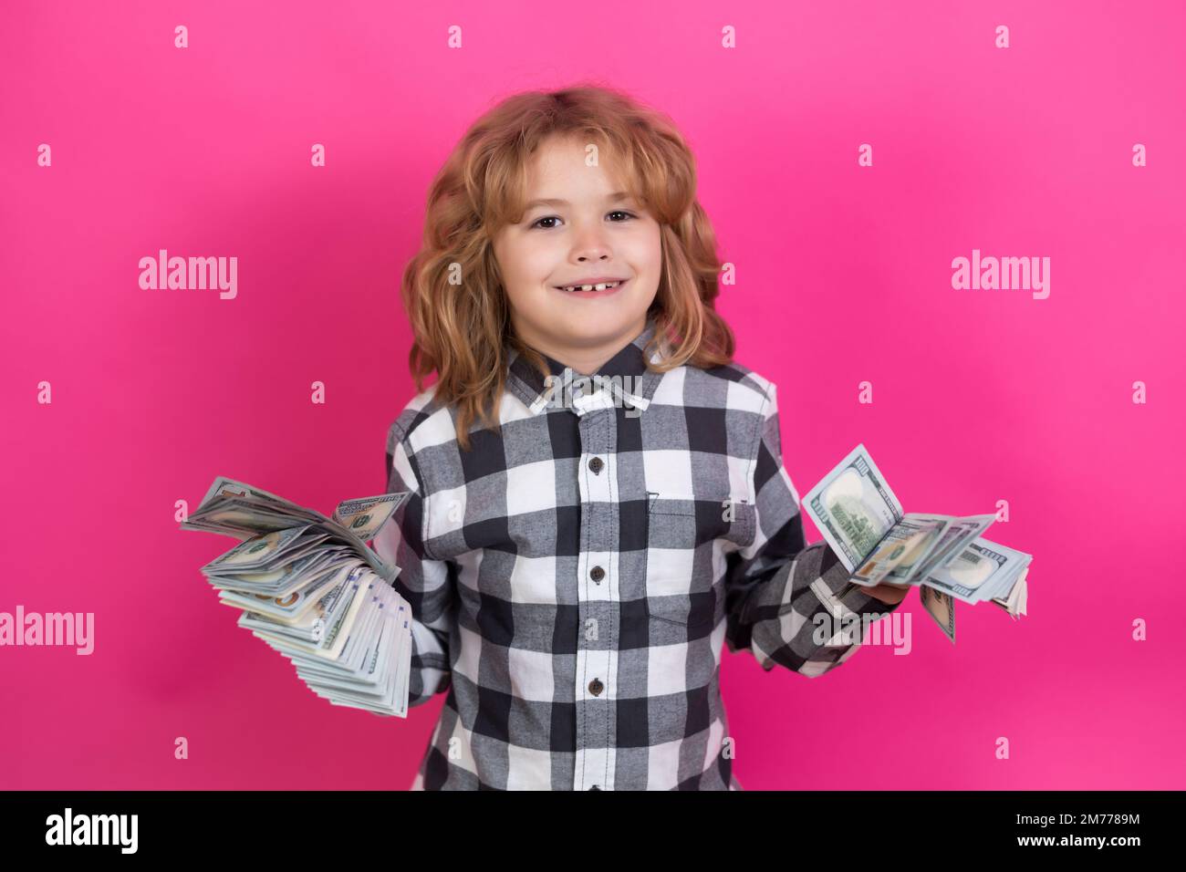 Child with lots of money dollar banknotes isolated over pink red studio ...