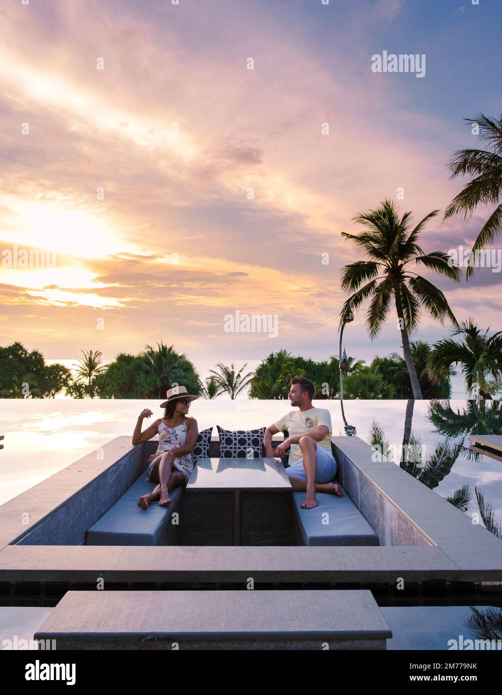 couple watching the sunset in an infinity pool on a luxury vacation in ...