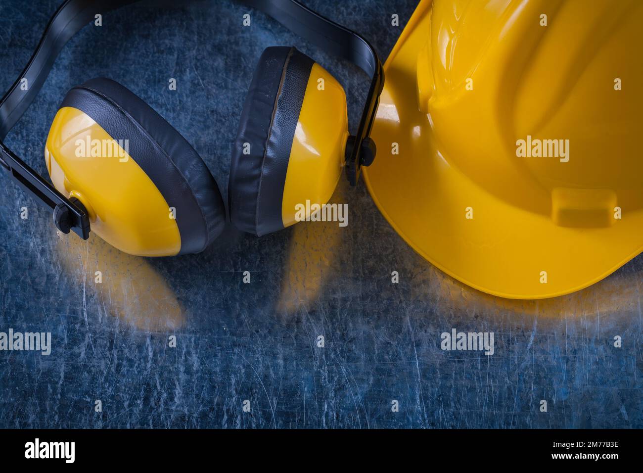 Noise reduction yellow headphones and work building helmet on scratched ...