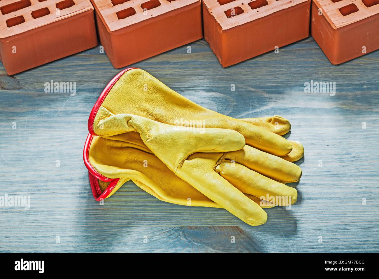 Orange bricks yellow safety gloves on wooden board bricklaying concept ...
