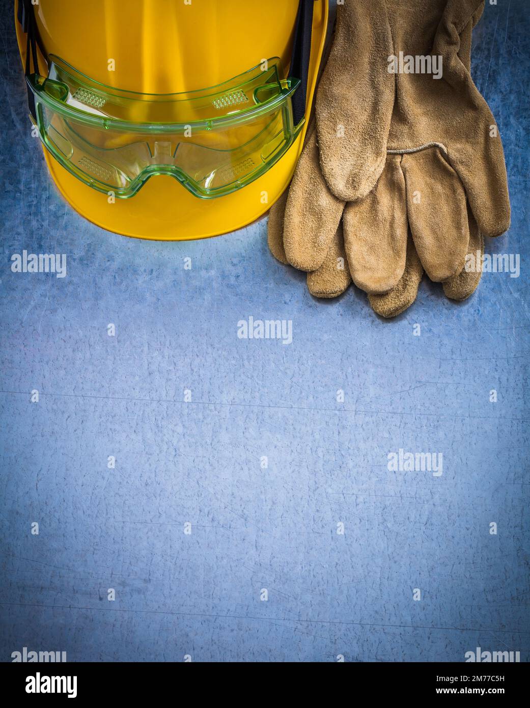 Pair of safety leather gloves building helmet and protective goggles on ...