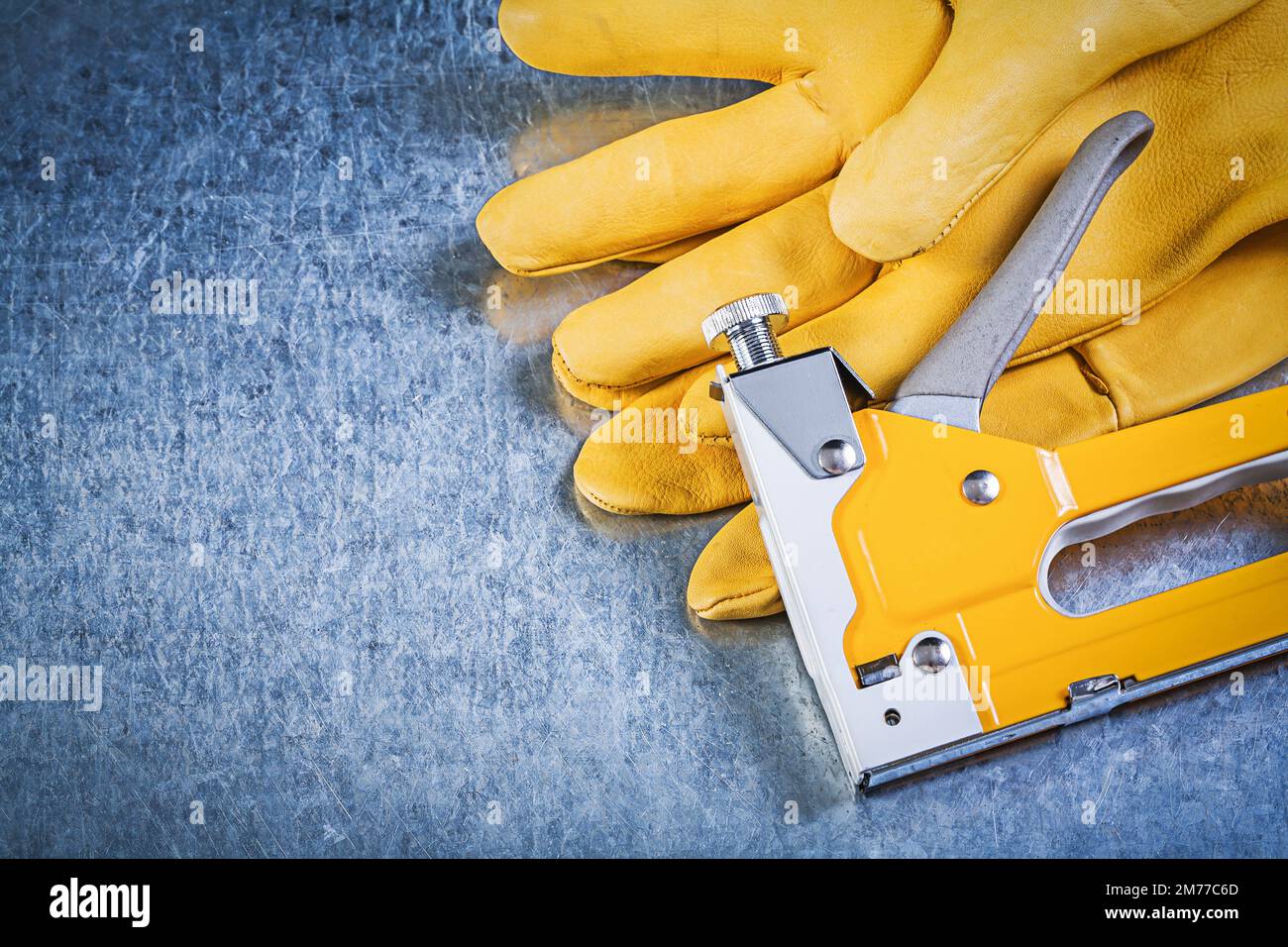 Pair of safety gloves staple gun on metallic background construction ...