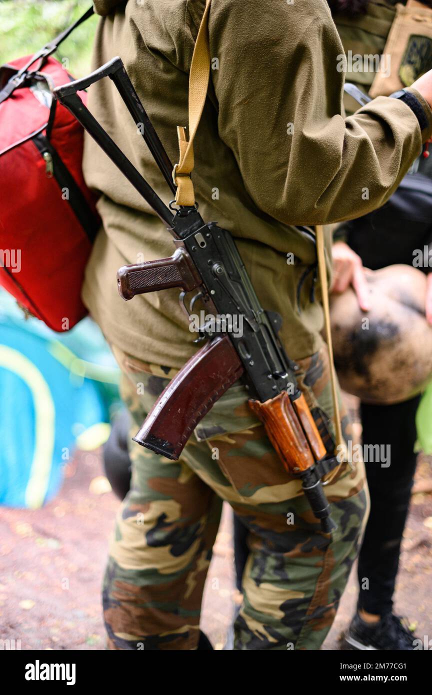 An automatic rifle hangs on the shoulder of a female soldier, close-up ...