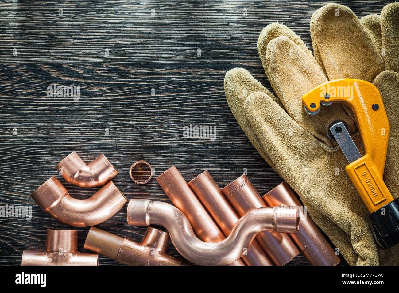 Plumbing brassware pipe cutter safety gloves on wooden board Stock ...