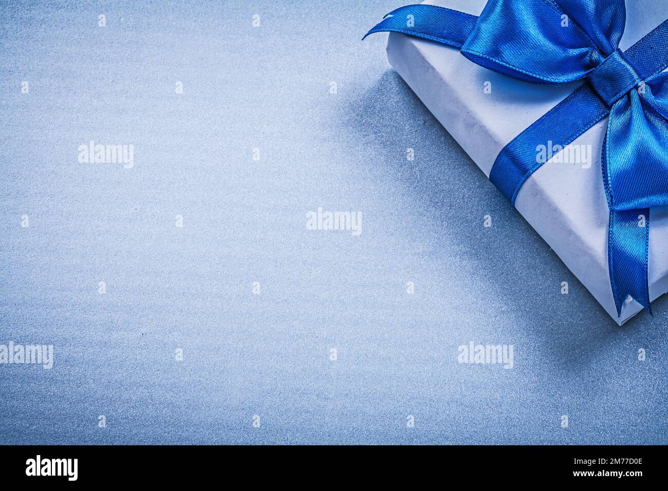 Present box with bow on blue background copyspace holidays concept ...