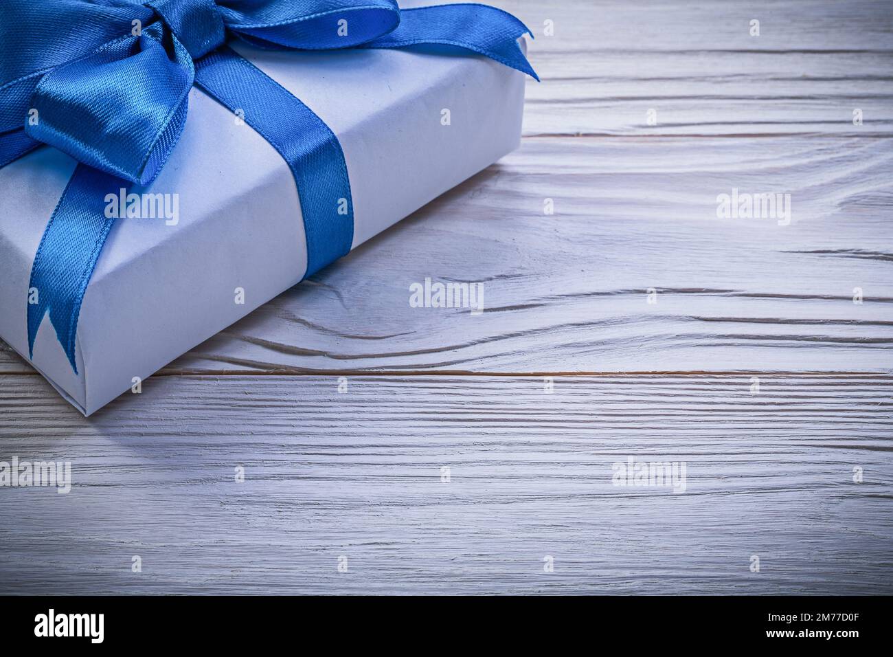 Present box with blue knot on wooden board celebrations concept Stock ...