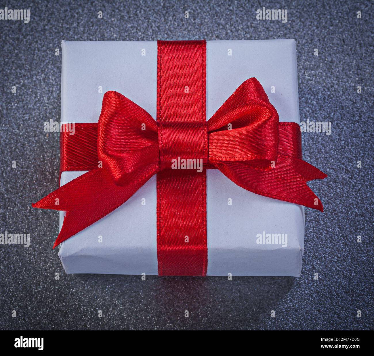 Present box with red tied tape on grey surface top view holidays ...