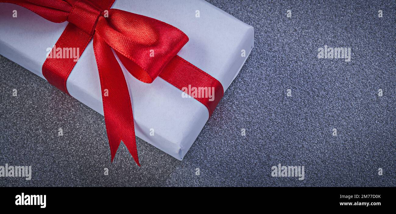 Present box with red knot on grey surface holidays concept Stock Photo ...