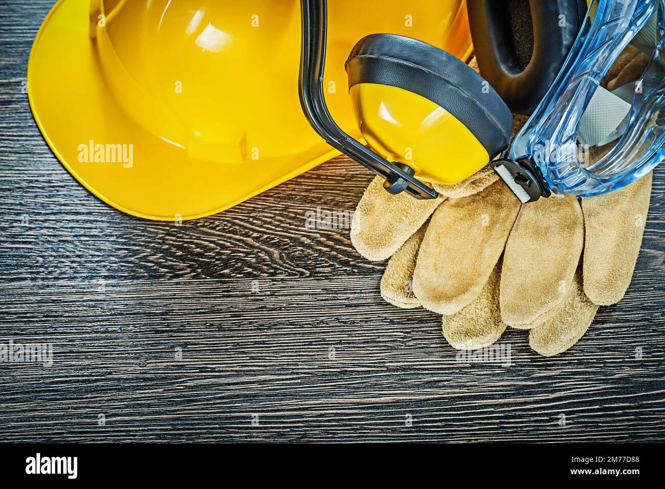 Protective gloves glasses earmuffs building helmet on wooden board ...