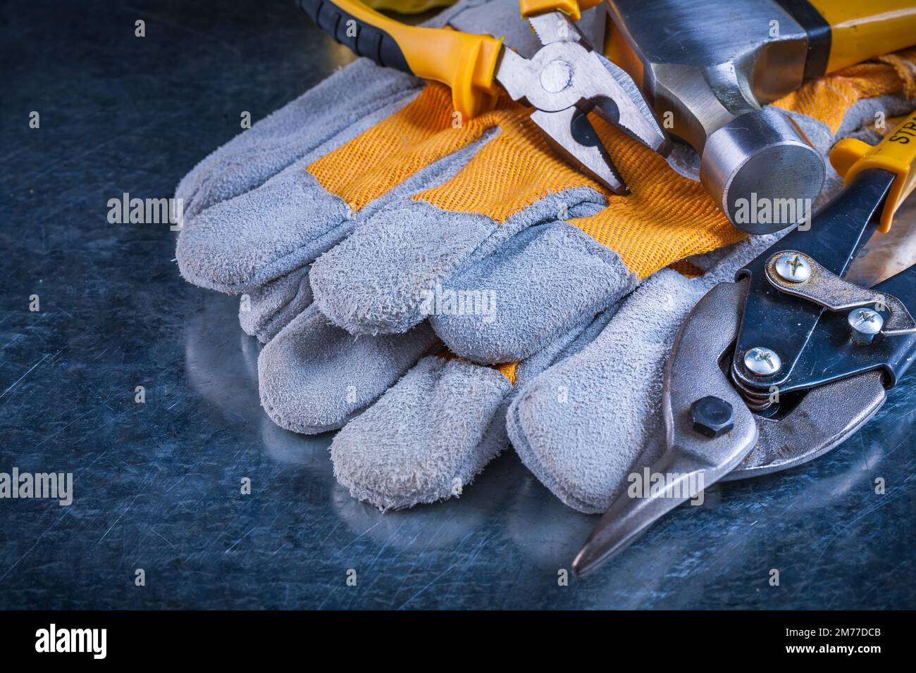 Protective gloves with claw hammer pliers and tin snips on scratched ...