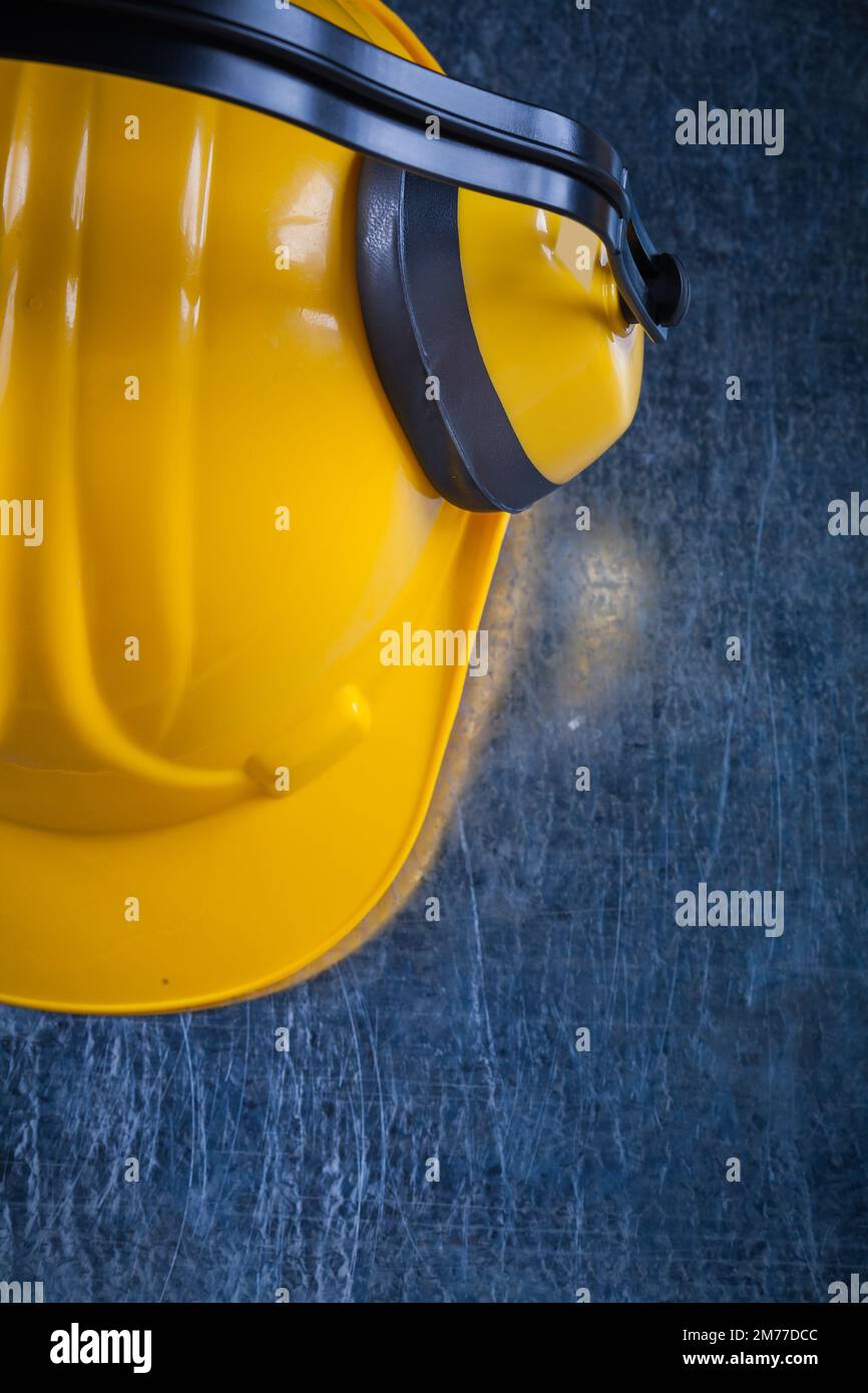Protective working helmet with safety ear muffs on scratched metallic ...