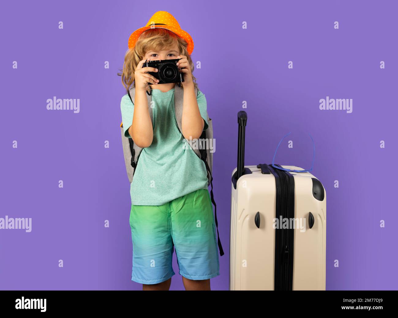 Child traveler with suitcase isolated on studio background. Tourist kid ...