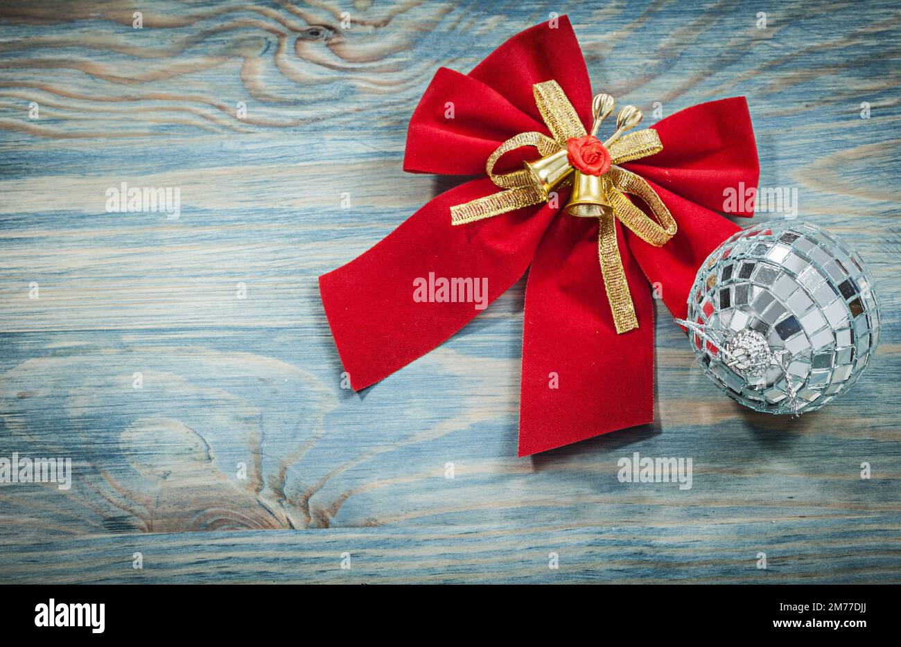 Red Christmas bow with bell disco bauble on wooden board celebrations ...