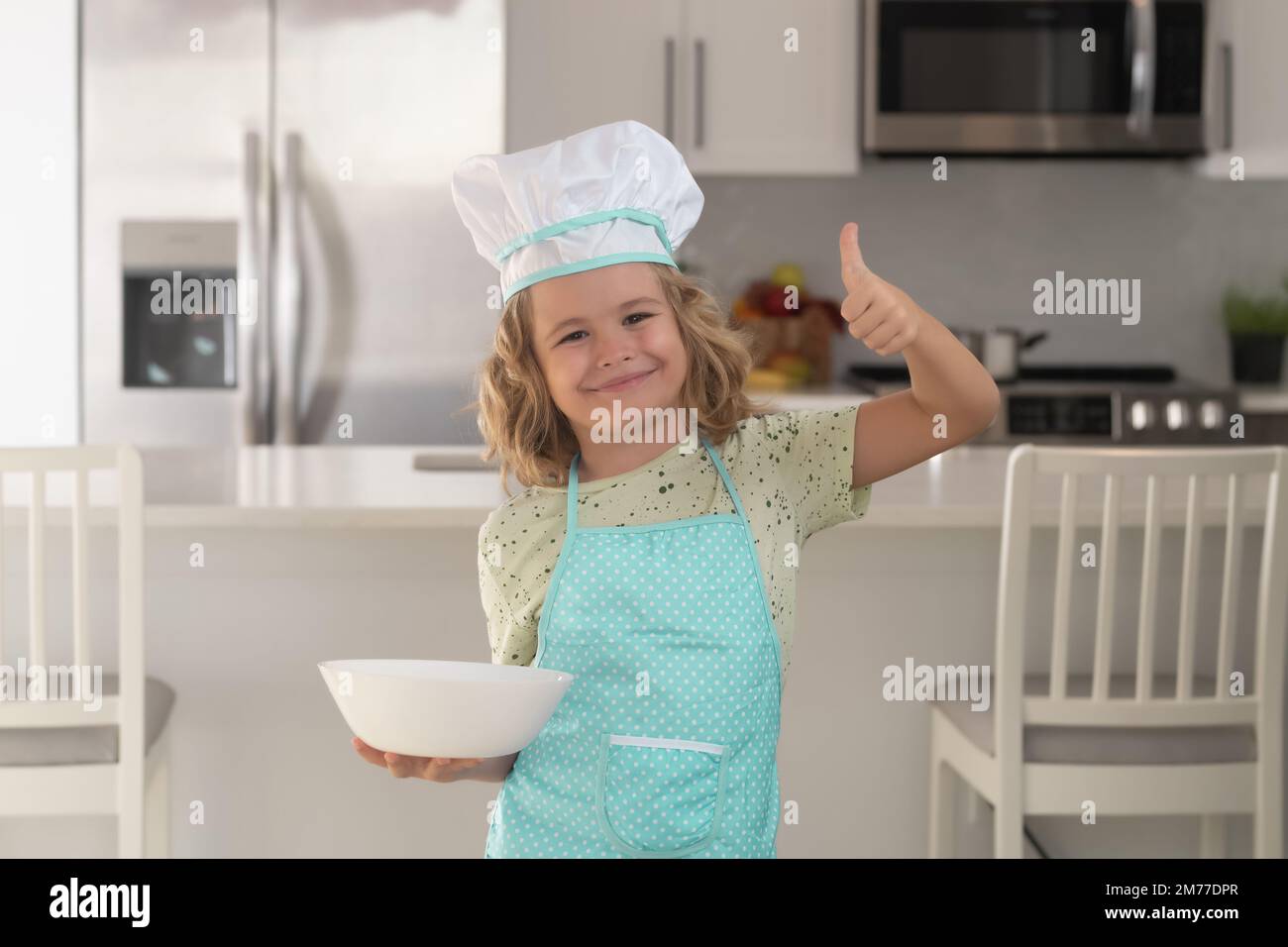 Child chef cook with cooking plate. Child chef cook is learning how to ...