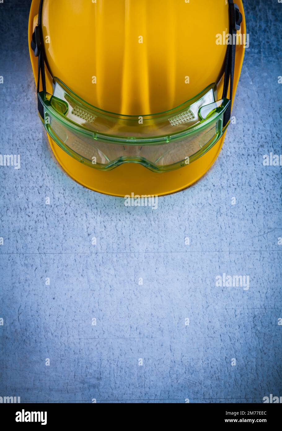 Safety building helmet and plastic glasses on metallic background ...