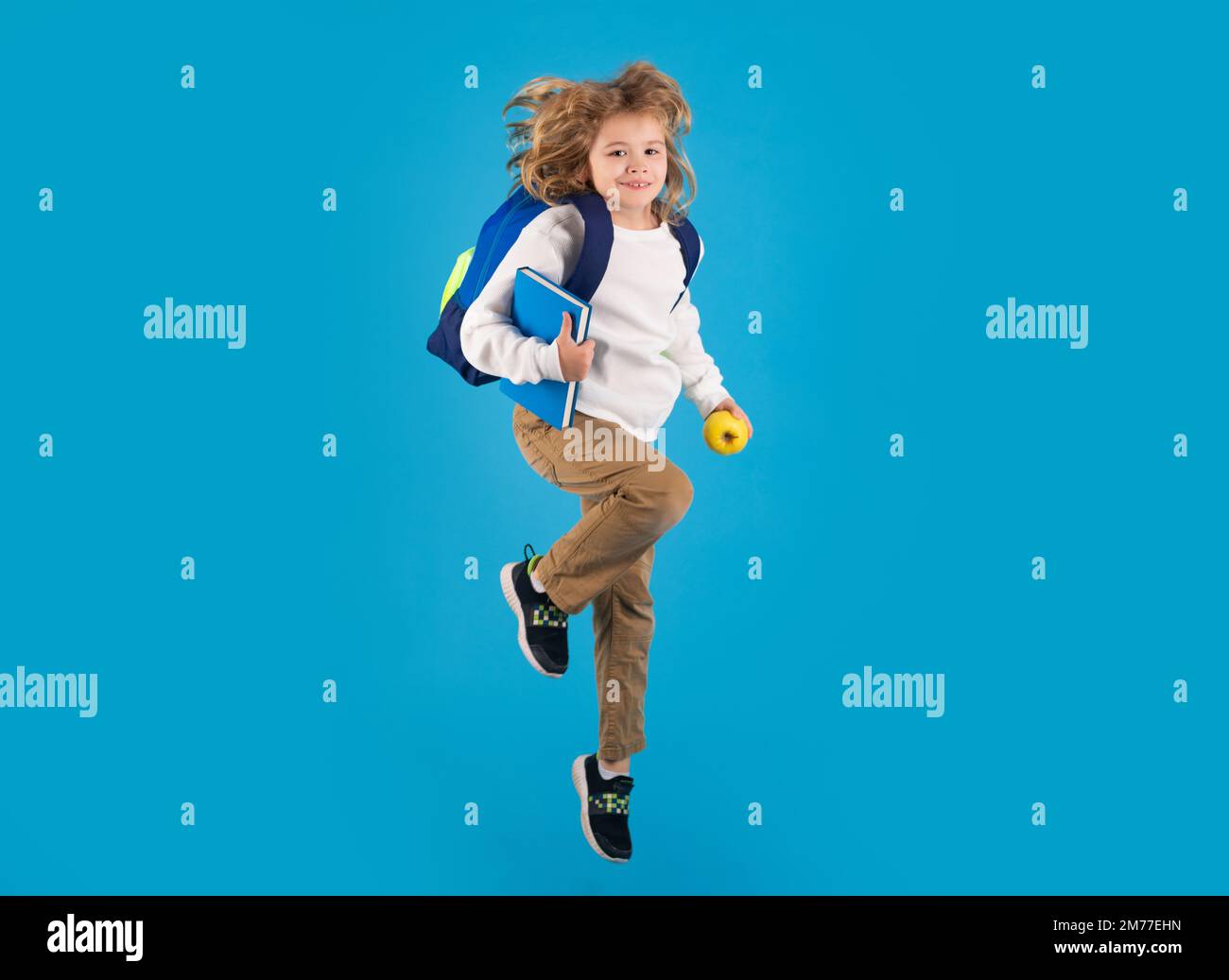 Kid jump and enjoy school. School child in school uniform with bagpack ...