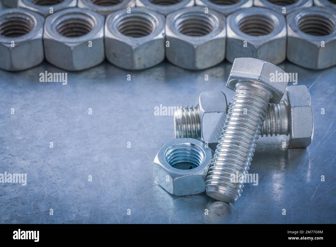 Stack of nuts bolt on scratched metallic background construction ...
