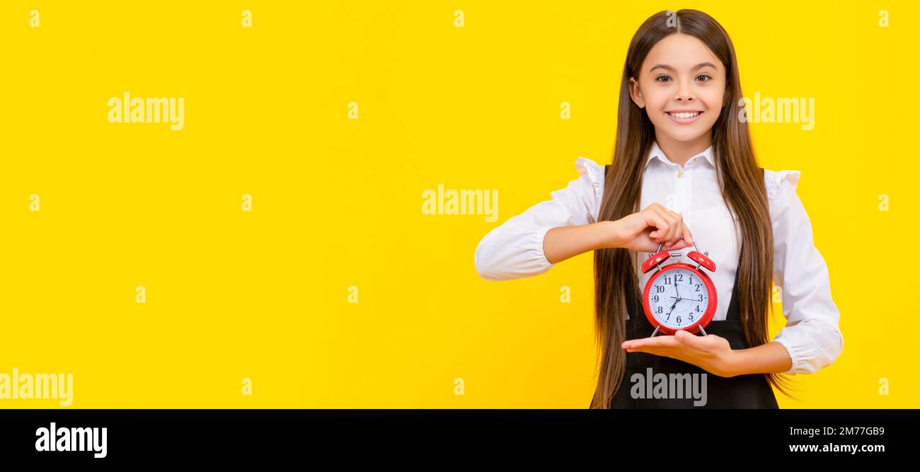 cheerful kid in school uniform with alarm clock showing time on yellow ...