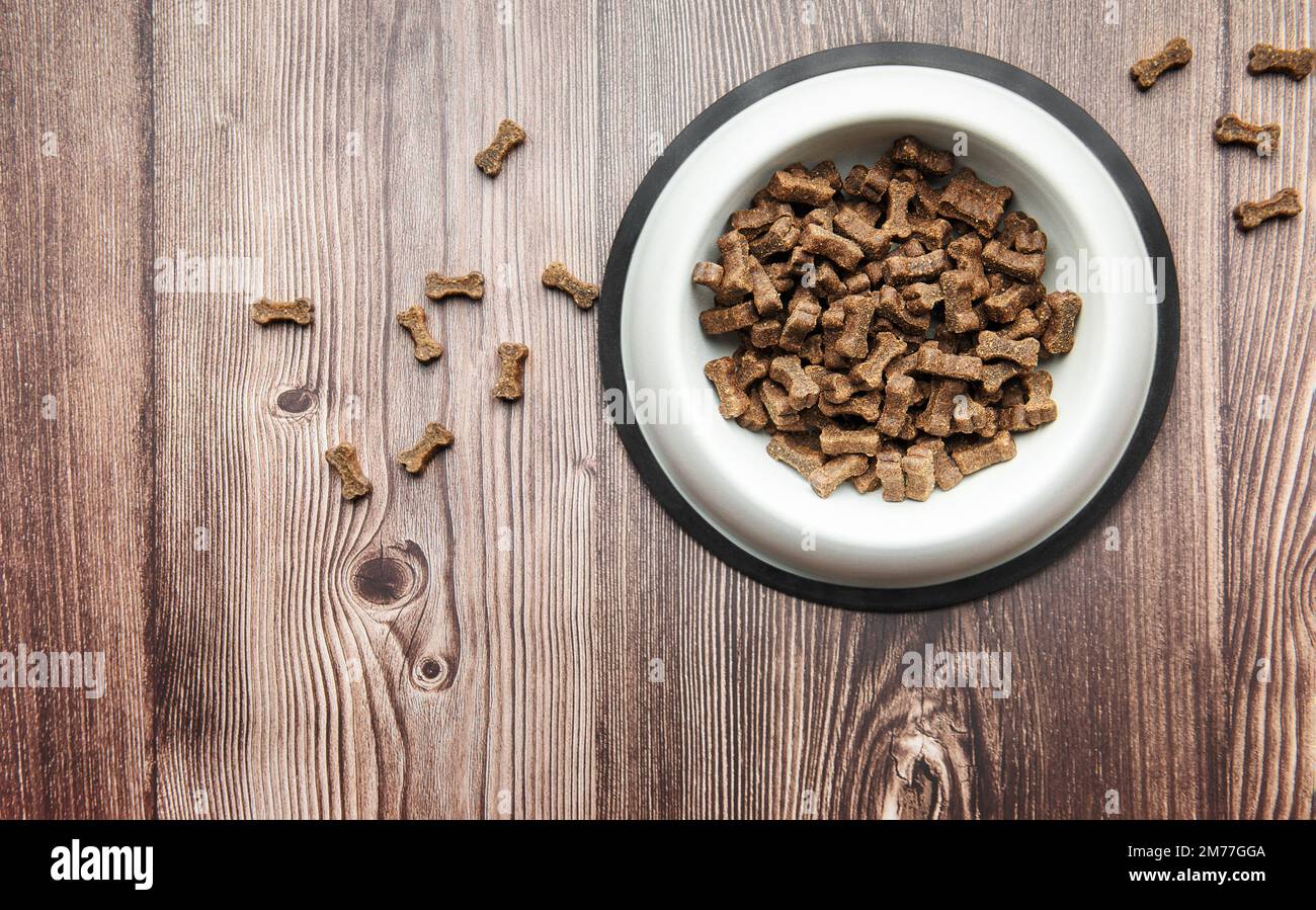 A bowl of dog food on a wooden floor. Granules of dry fodder in the ...