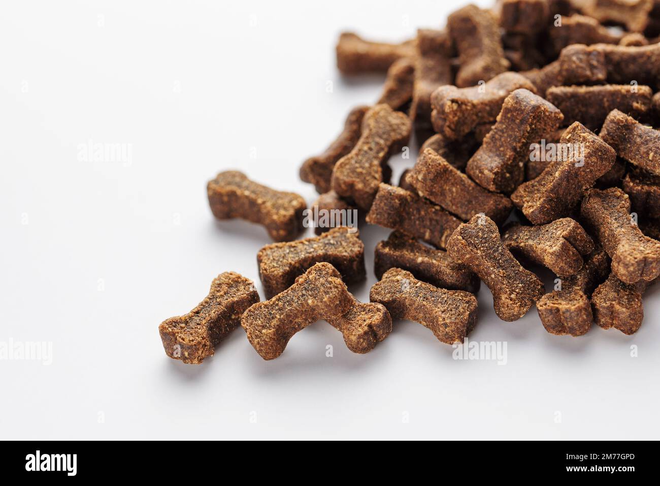 Granules of dry feed in the shape of a bone for dogs on a white ...