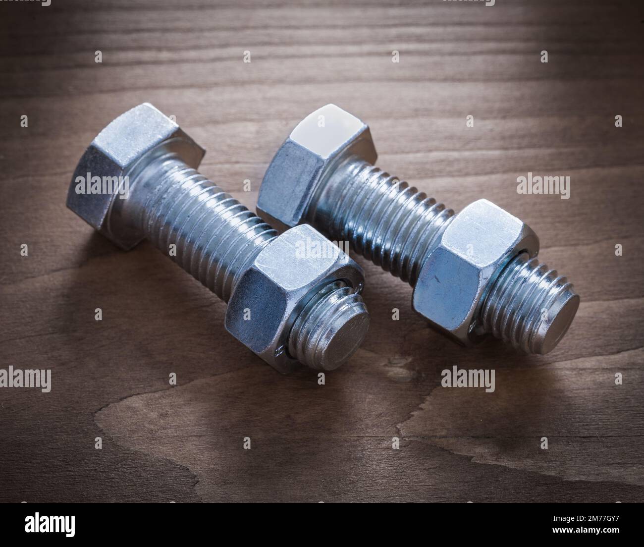 Threaded bolts and nuts on wooden surface construction concept Stock ...