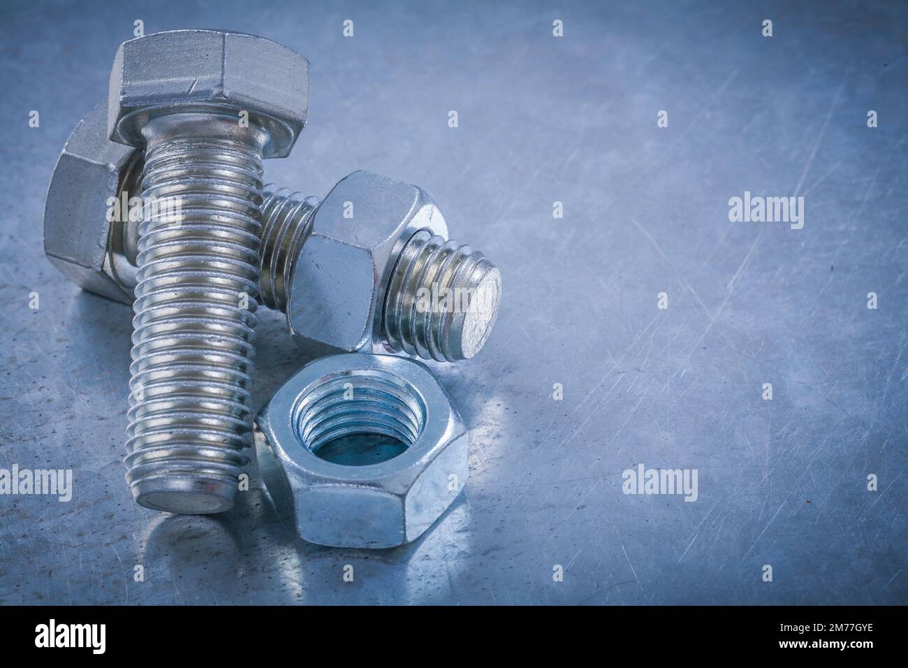 Threaded bolts construction nuts on scratched metallic background ...