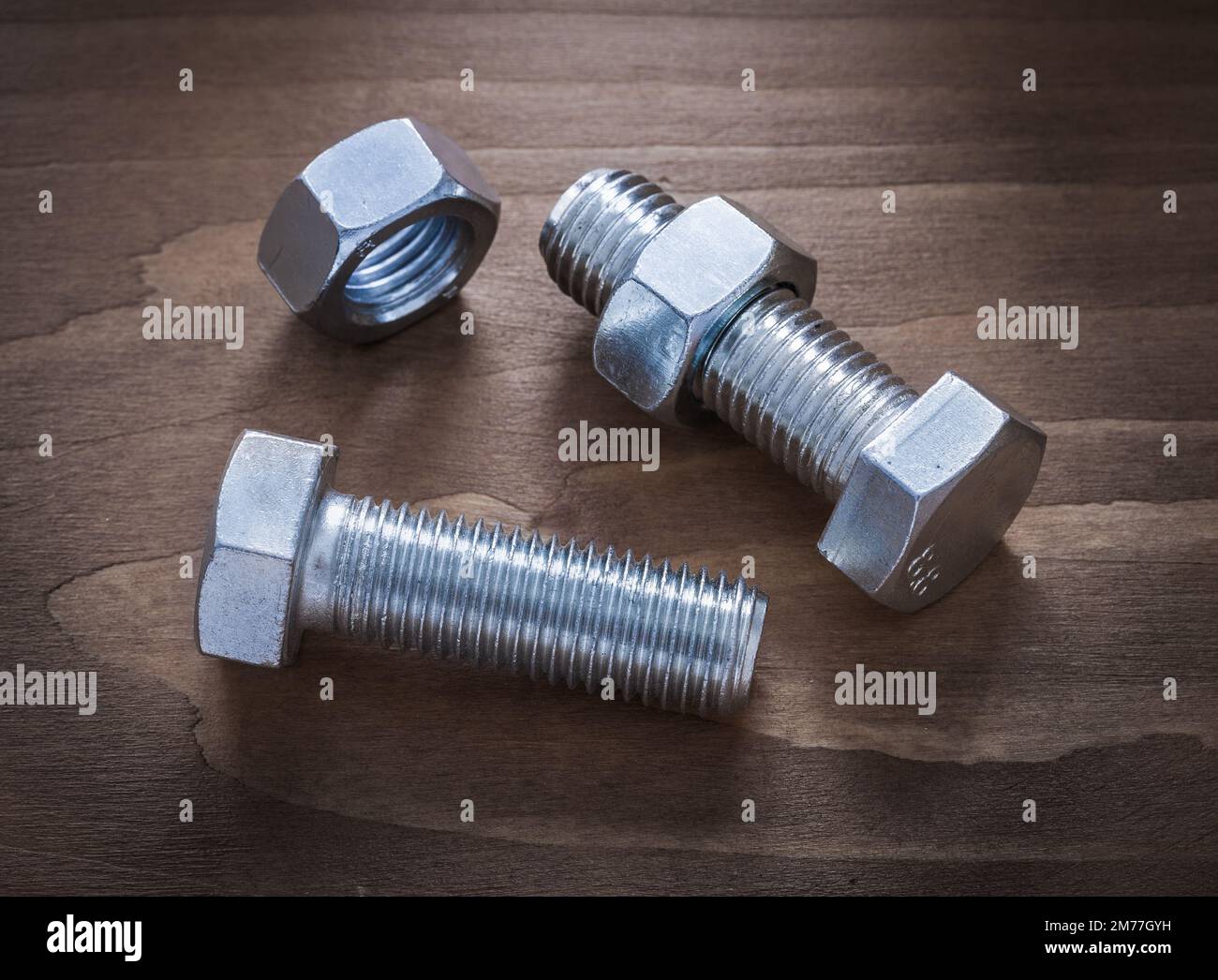 Threaded bolts and screw- nuts on wooden board construction concept ...