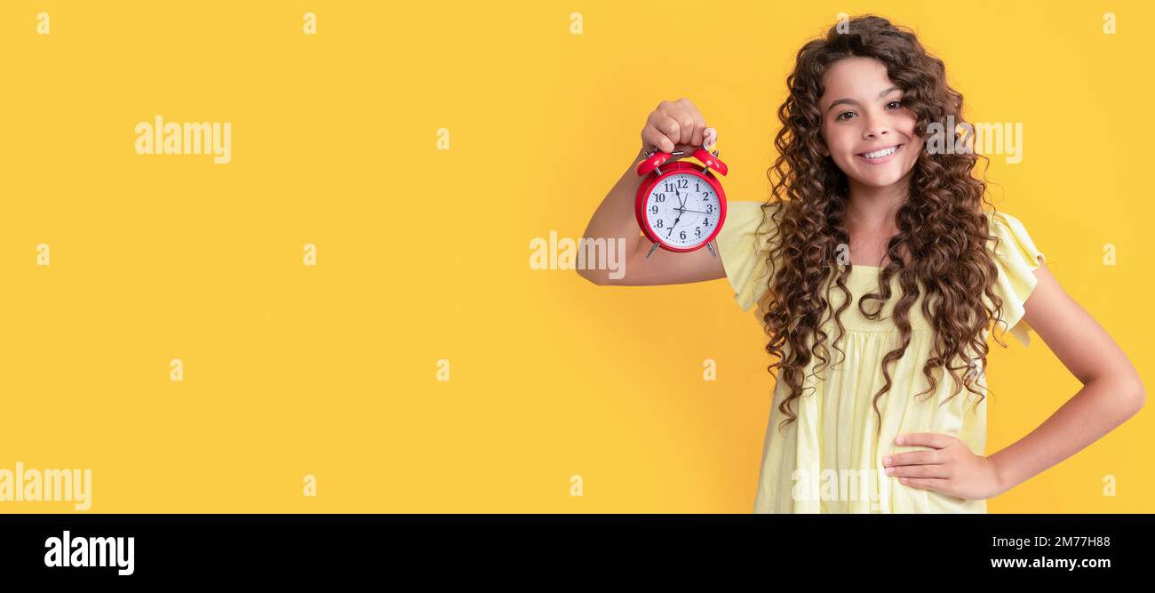 cheerful child with alarm clock. school kid curly hair showing clock ...