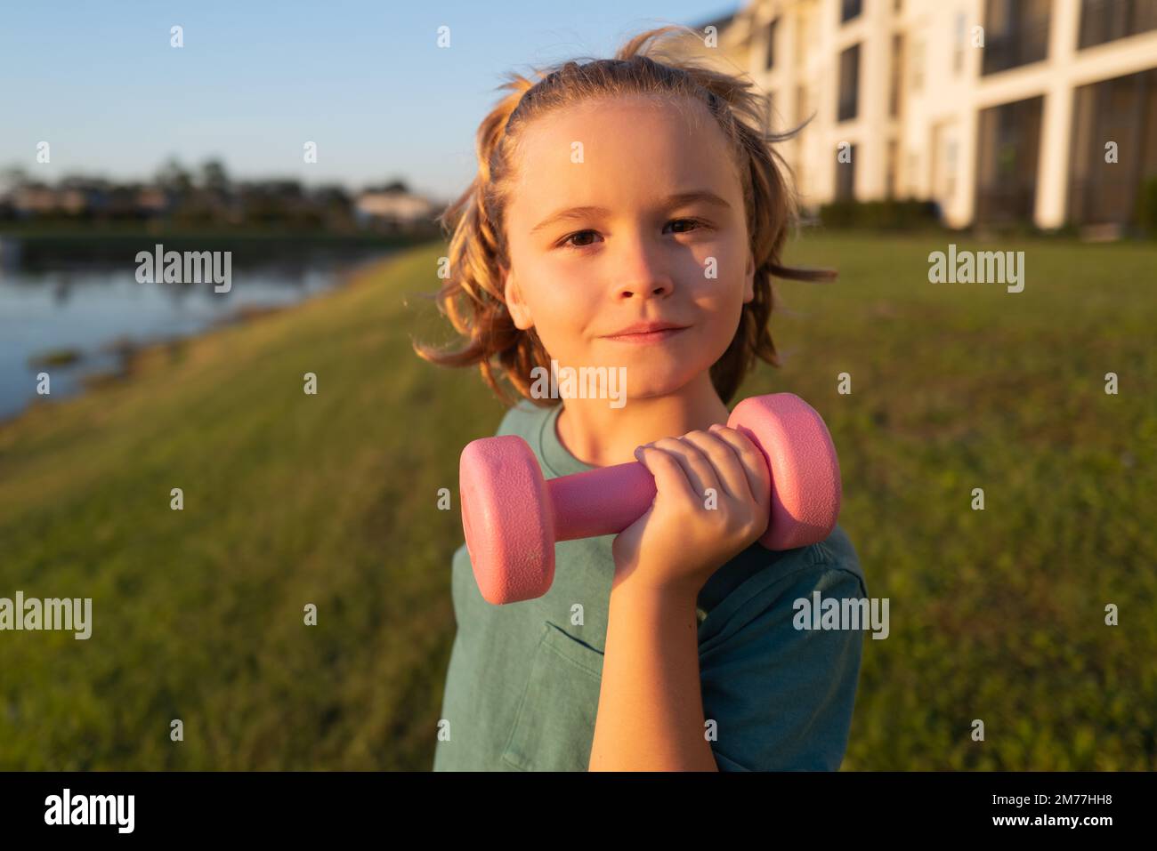Kids sport training outdoor. Child boy pumping up biceps muscles with ...