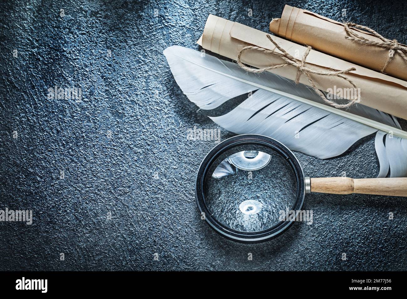 Vintage corded paper rolls magnifying glass feather on black background ...