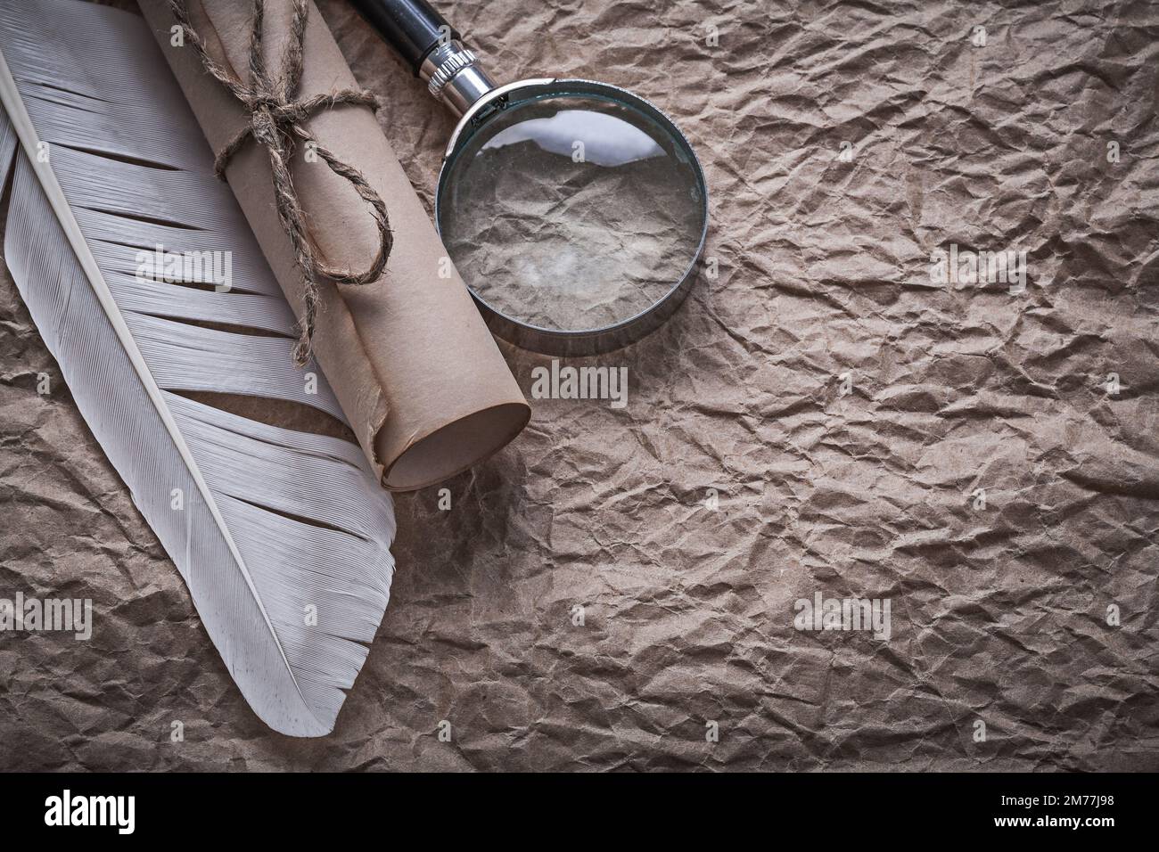Vintage feather loupe corded rolled document on messy crumpled paper ...