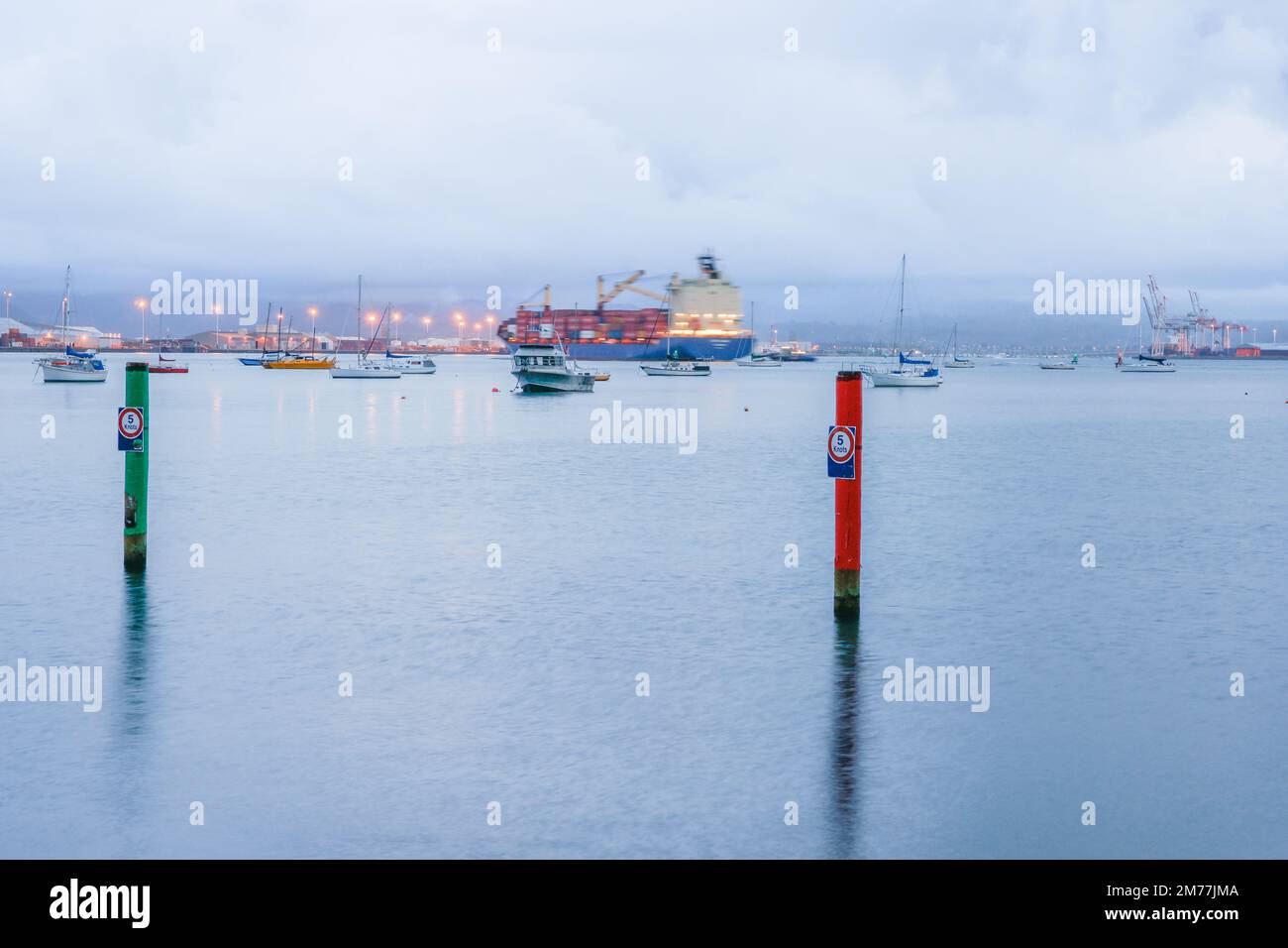 Five knot signs on boat ramp navigation poles with blurred image of ...