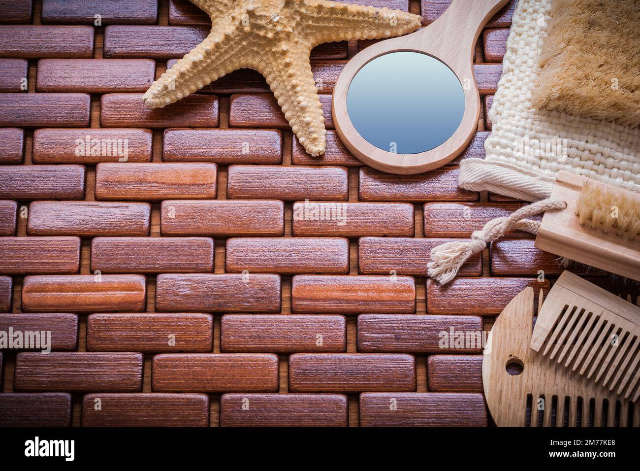 Wisp of bast loofah combs starfish and looking-glass on textured wooden ...
