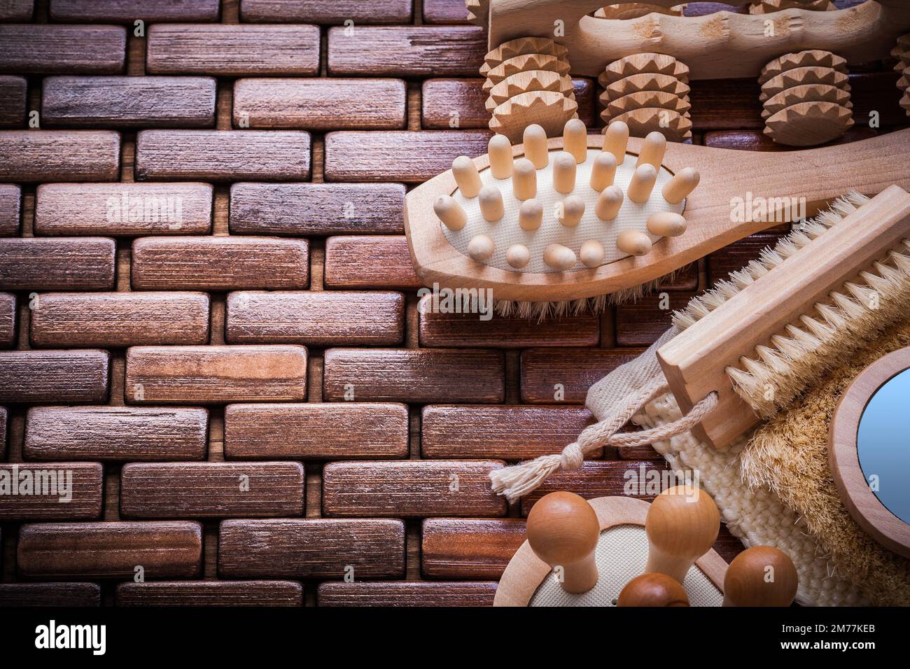 Wisp of bast loofah massagers and brush on textured wooden mat sauna ...
