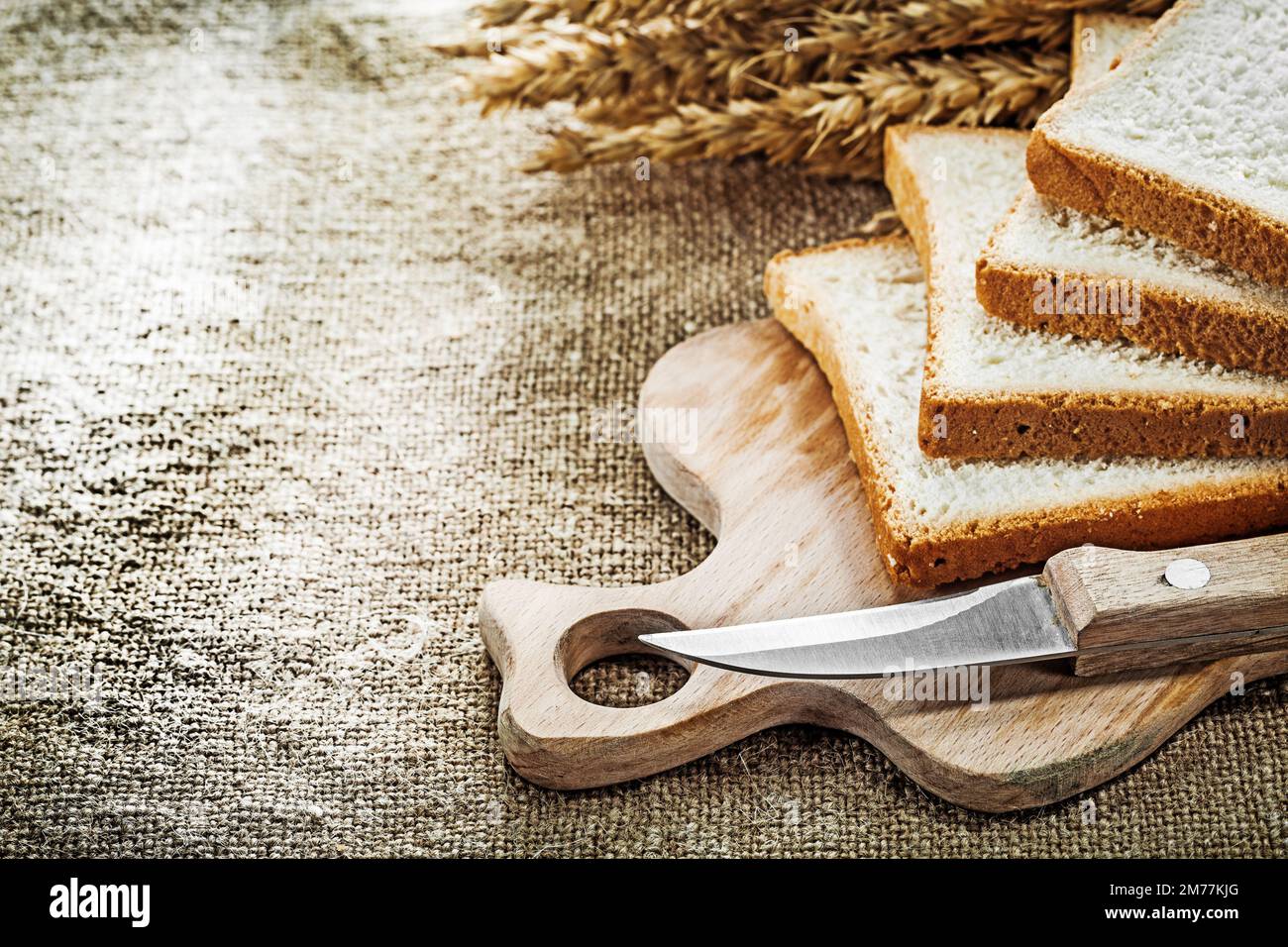 Wooden chopping board knife sliced bread wheat ears on hessian ...