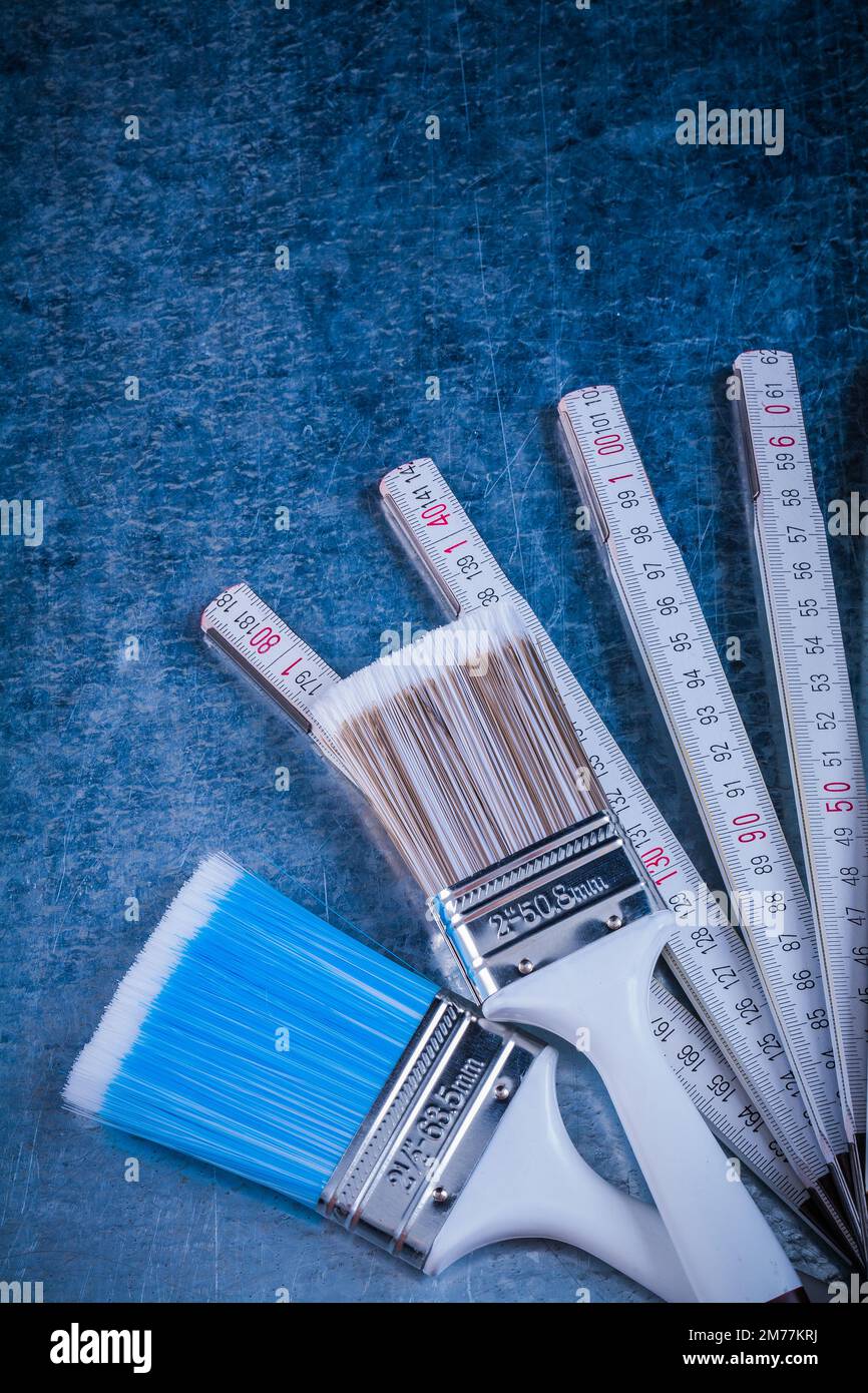 Wooden meter paint brushes on scratched metallic surface construction ...