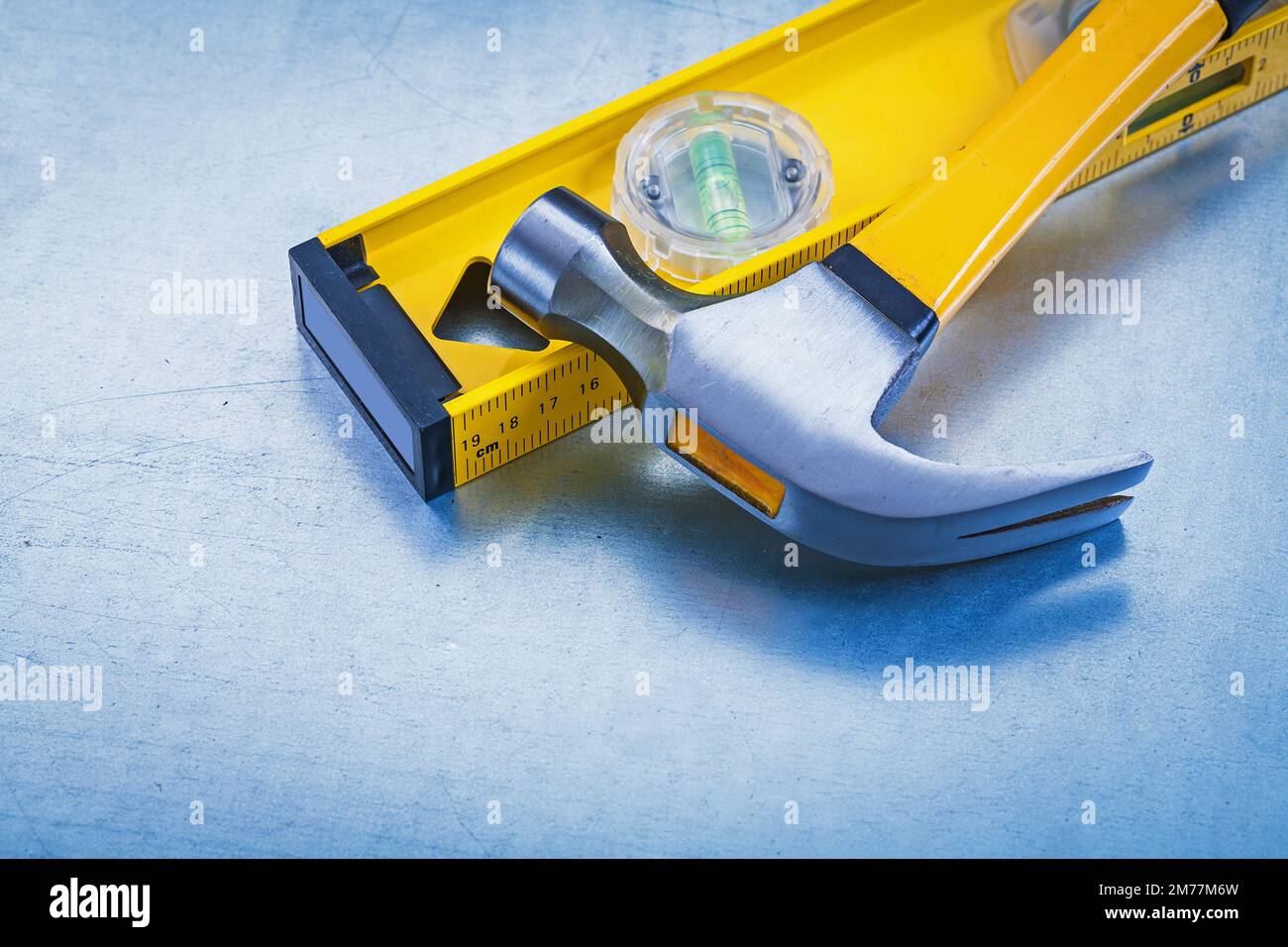 Yellow construction level and claw hammer on metallic background ...