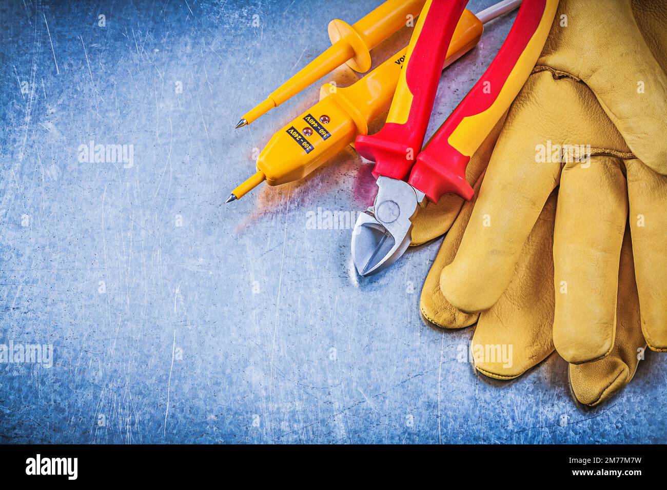 Yellow electrical tester safety gloves red wire cutter on metallic ...
