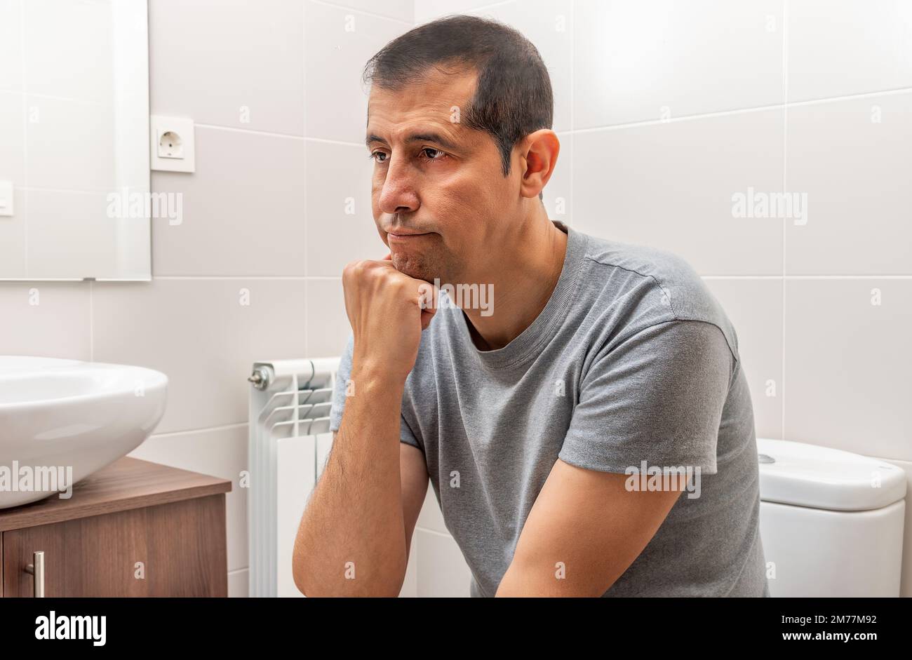 Shot of an bored and constipated man using the toilet at home Stock ...