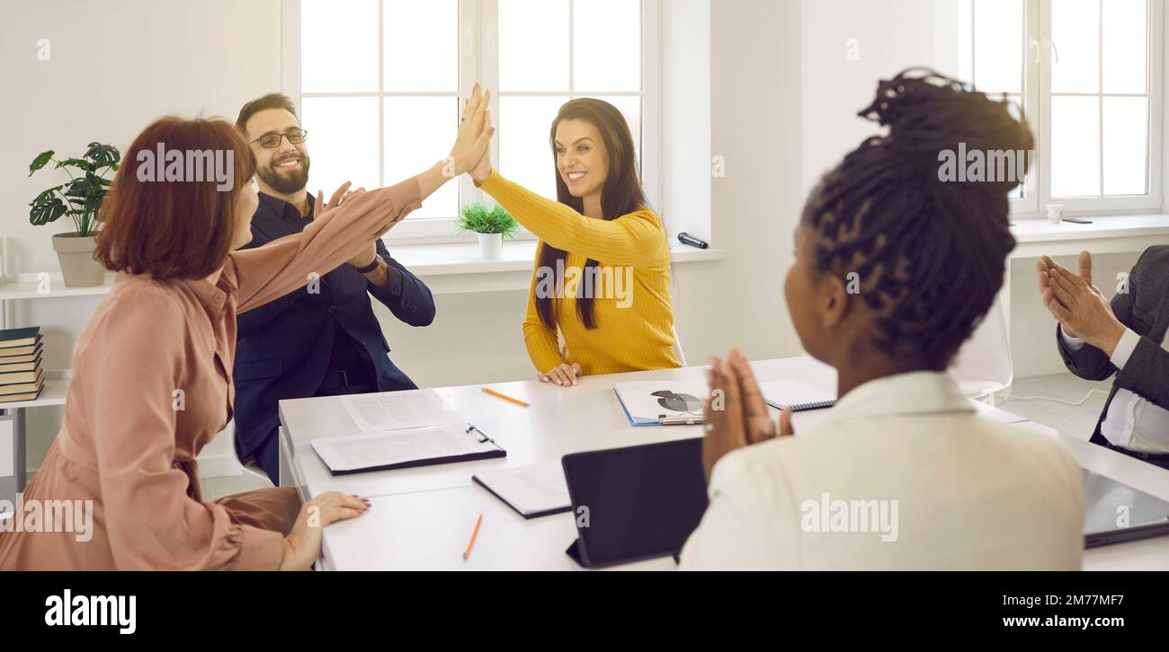 Happy women high five each other as they celebrate success during ...