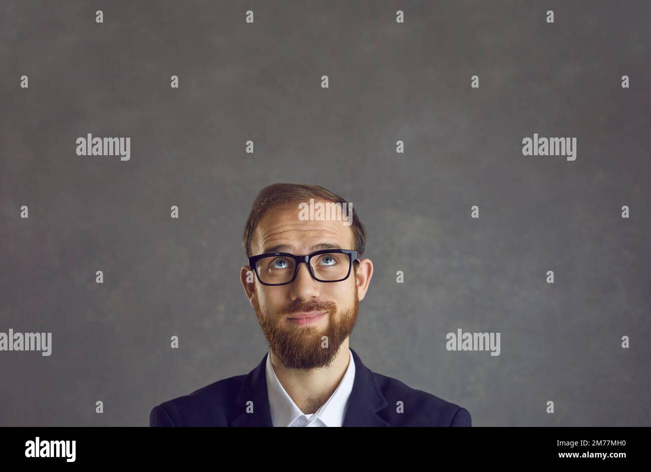 Portrait of unsure male employee with funny dreamy facial expression on ...