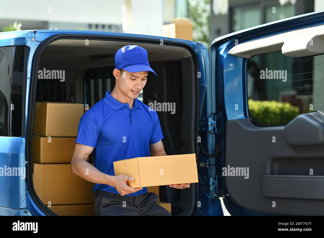 Delivery man sitting in open delivery van and checking checking address ...