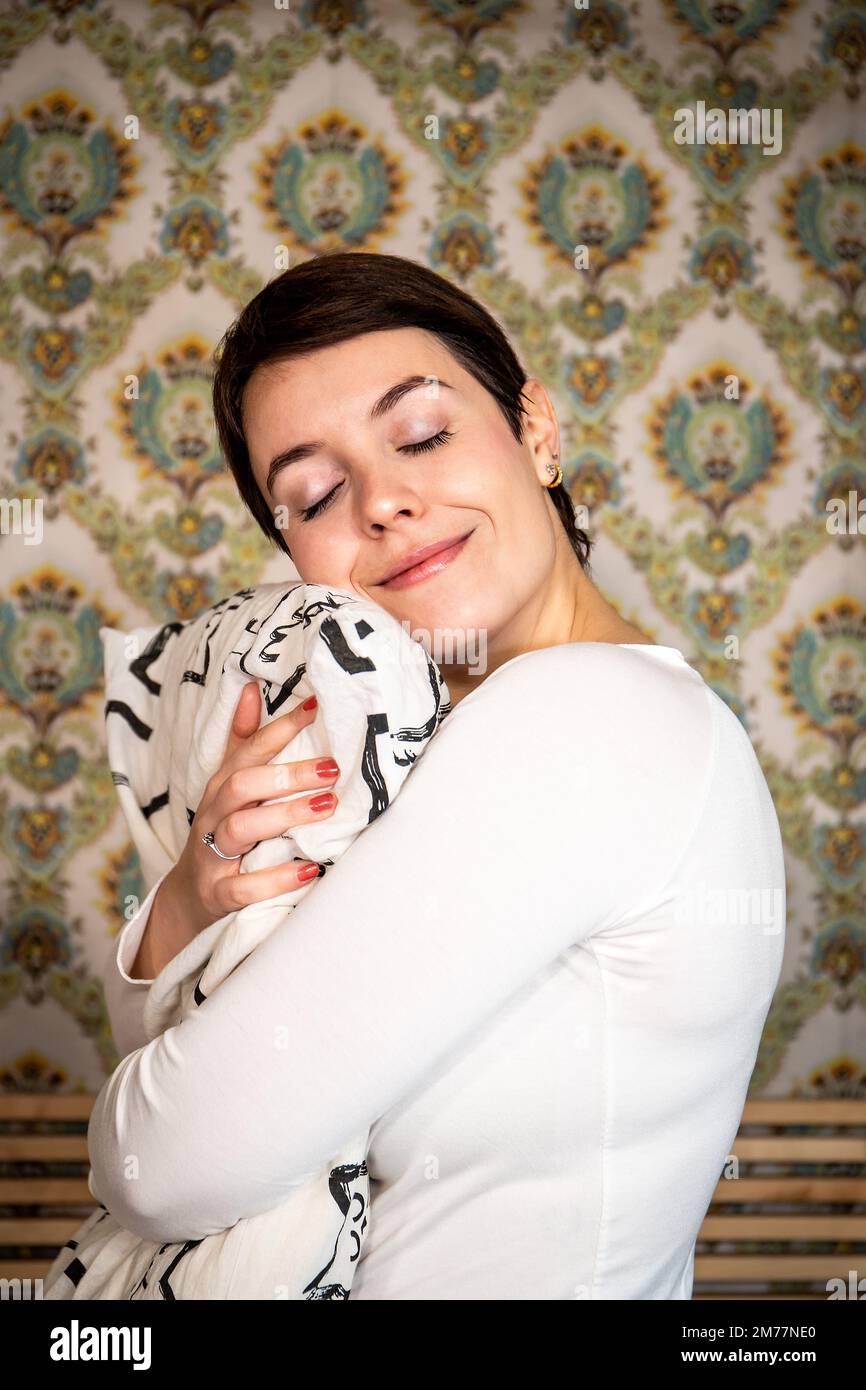 Short haired young woman closes her eyes and hugs the pillow. Concept ...