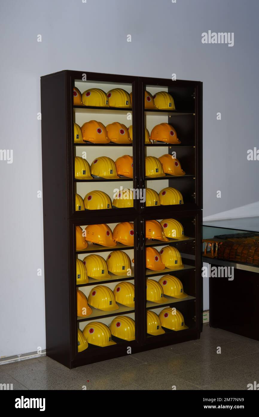 Yellow helmets of mine workers on the shelf with white wall at the ...