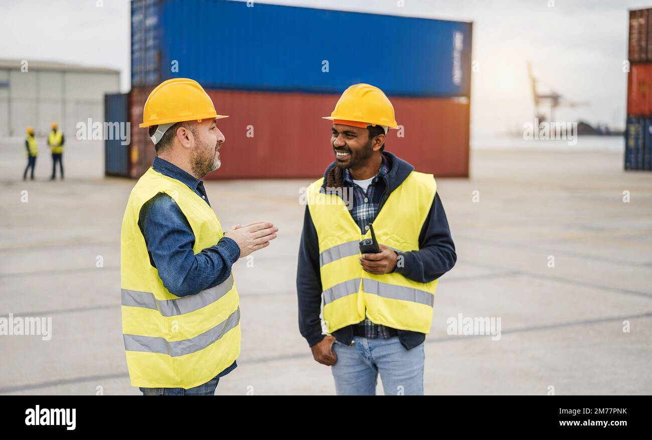 Multiracial workers controlling shipping containers at industrial port ...