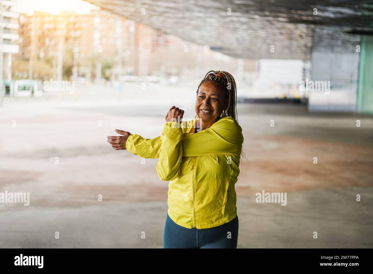 Senior african woman stretching during workout routine outdoor - Focus ...
