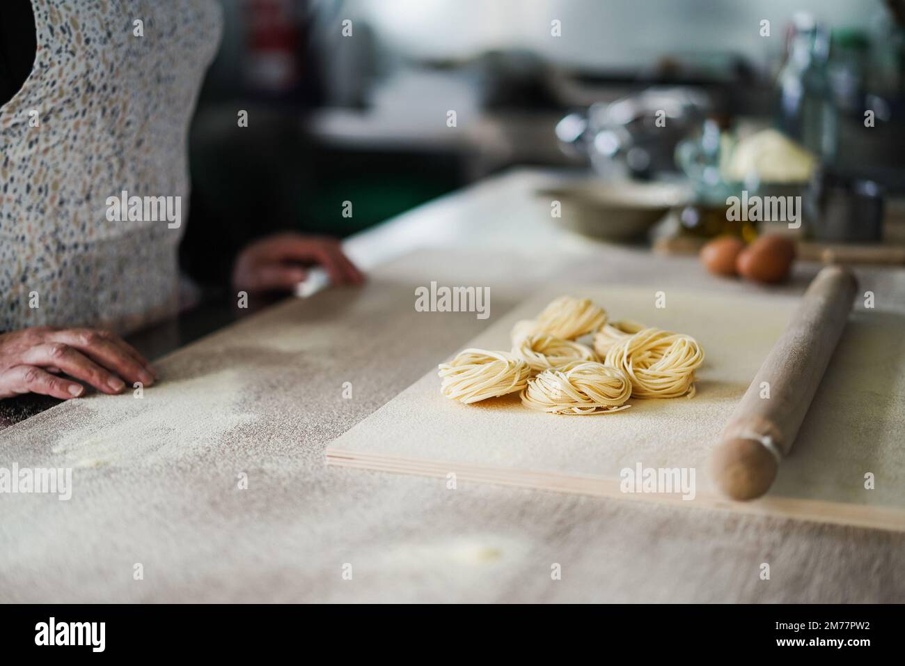 Woman preparing dough for ravioli inside pasta factory - Focus on pasta ...